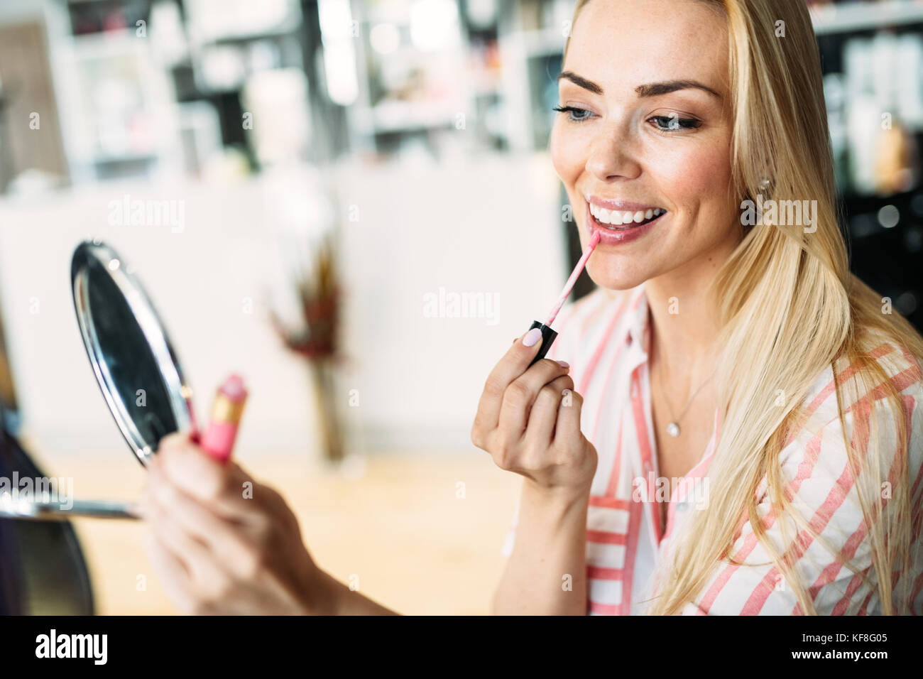 Young beautiful woman applying make up using small mirror Stock Photo ...