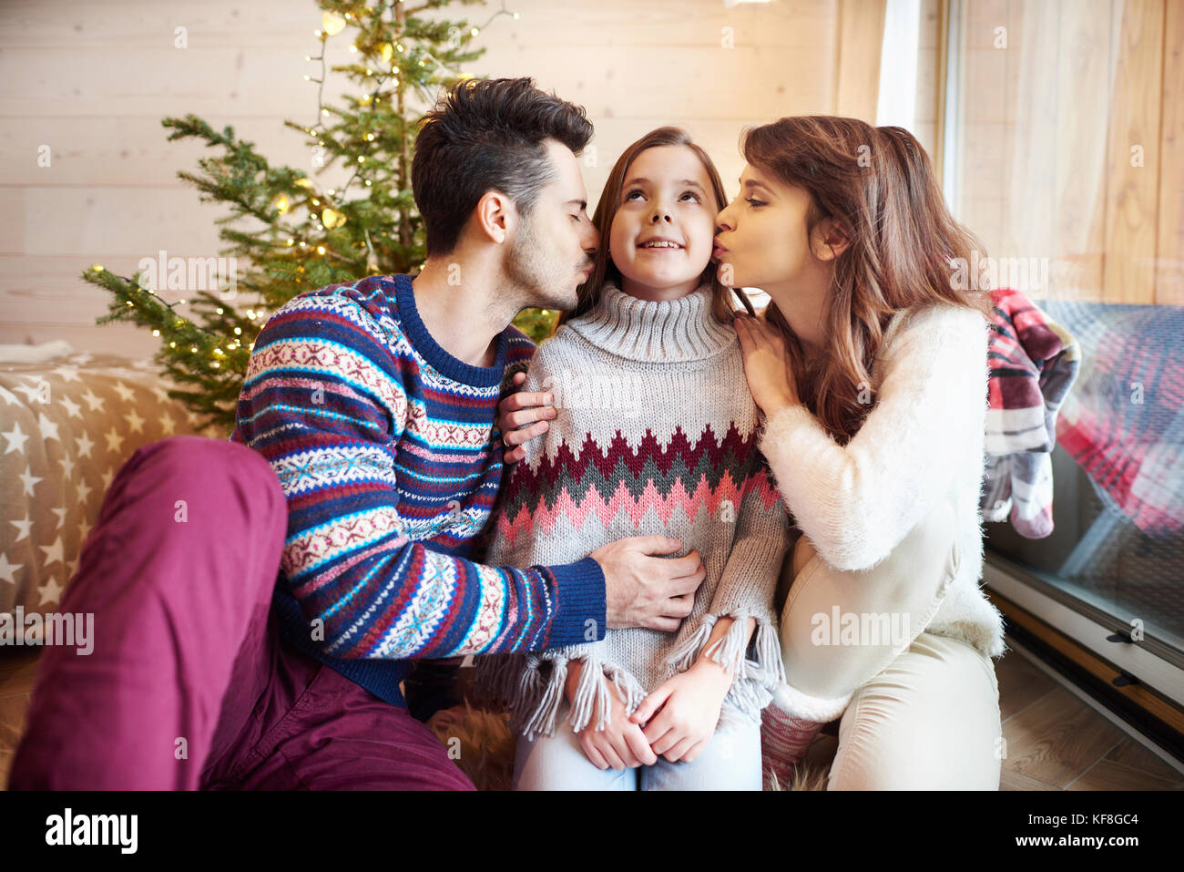 Thoughtful parents kissing their daughter Stock Photo - Alamy