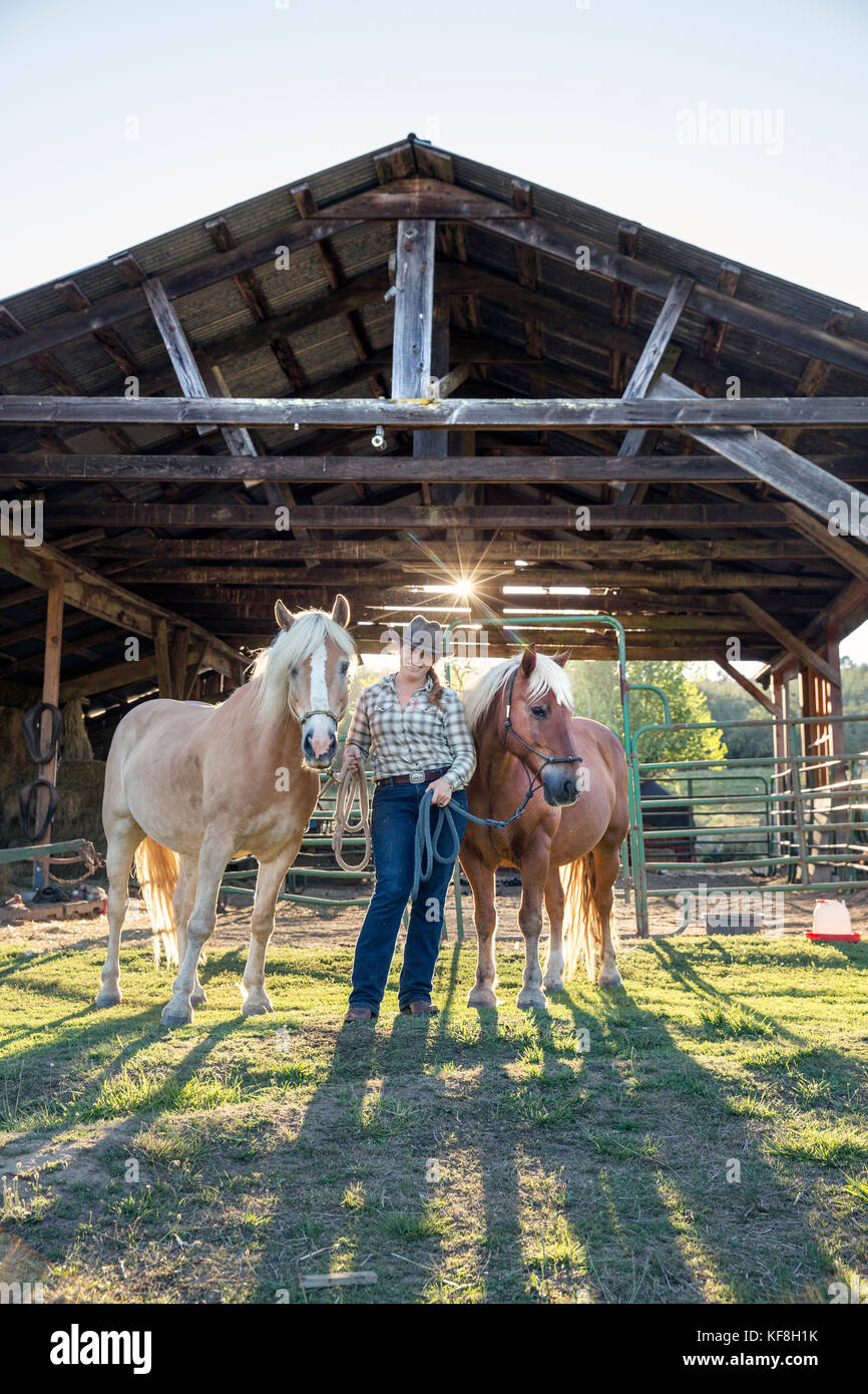 USA, Oregon, Willamette Valley, Clare Carver stands with her horses in ...