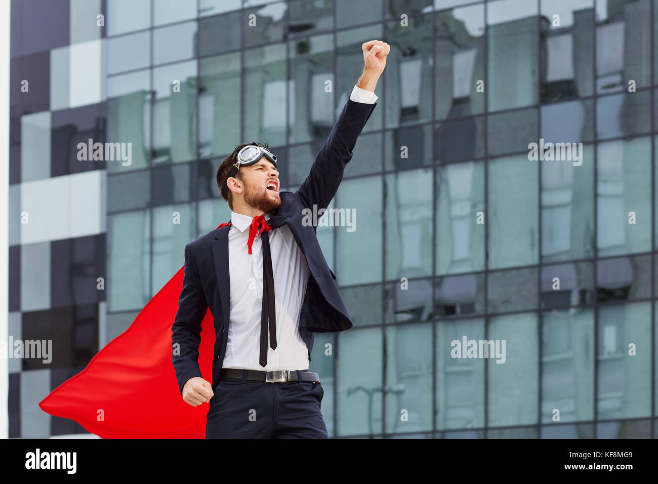 A superhero businessman is raising his hand up against a business ...
