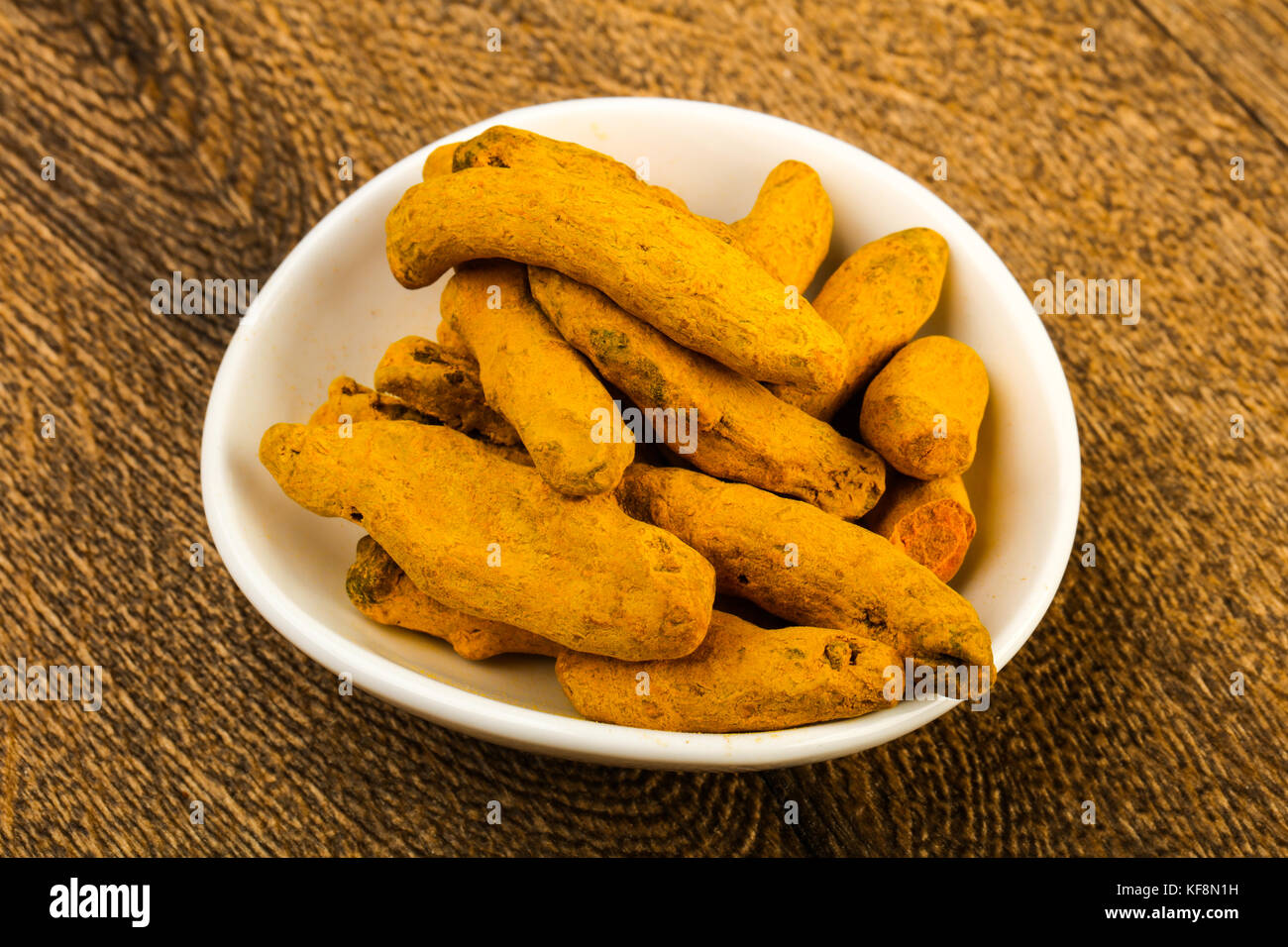 Tumeric roots heap in the bowl over wooden background Stock Photo - Alamy