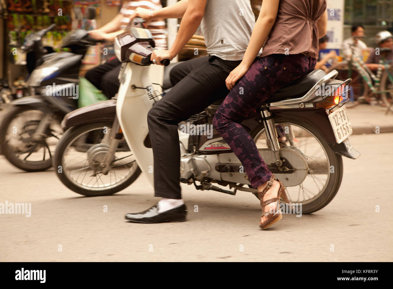 VIETNAM, Hanoi, a detail of a couple driving a moped through town ...
