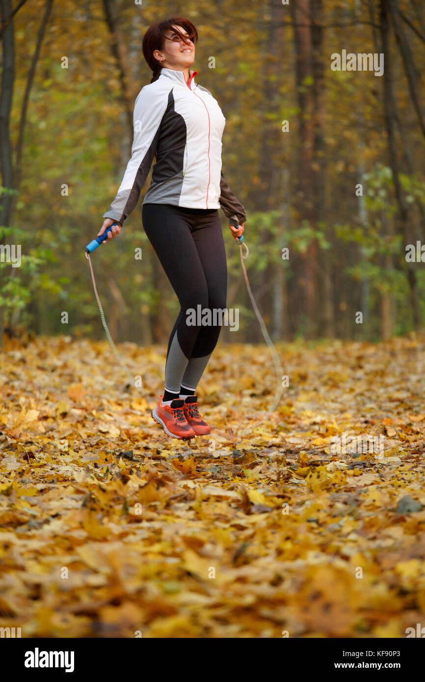 Side view of sporty woman jumping with rope at autumn forest Stock ...