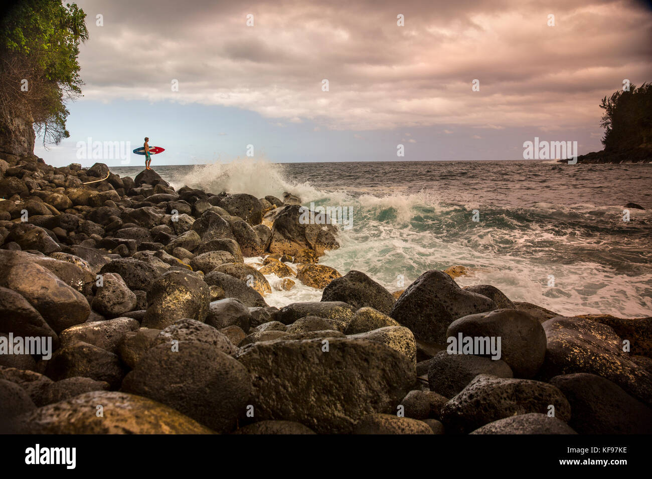 USA, Hawaii, The Big Island, surfer watches the waves on a rocky ...