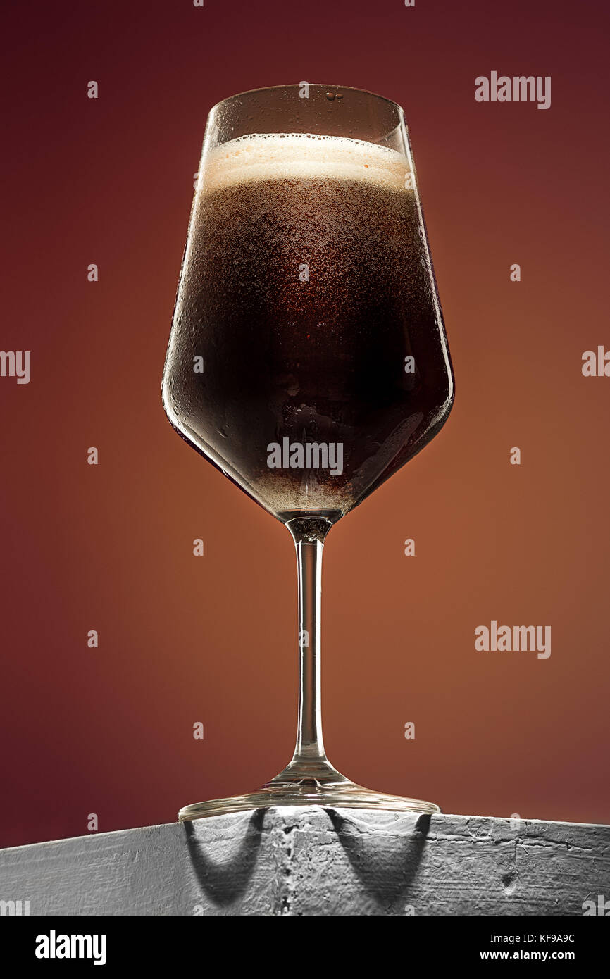 glass of cold frothy dark beer on an old wooden table Stock Photo - Alamy