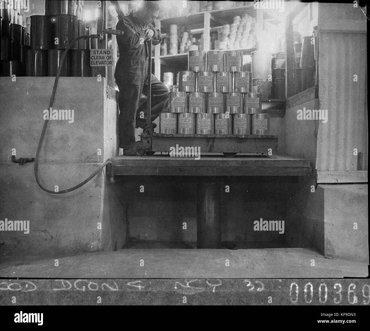 13582 A workman stacking a pallet of paint cans on the elevator Stock ...
