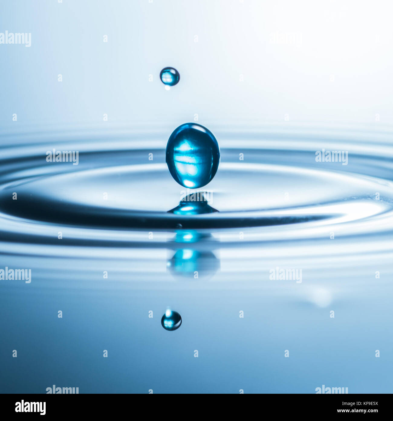 An abstract macro shot of water drops falling into a pool of water ...