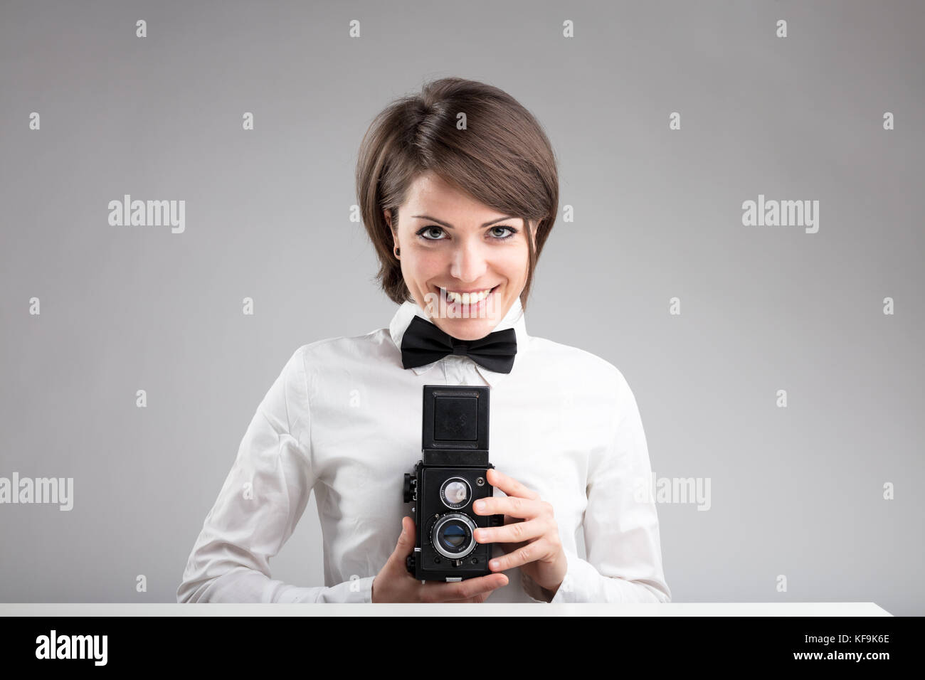 happy photographer in bow tie with a vintage twin-lens reflex camera ...