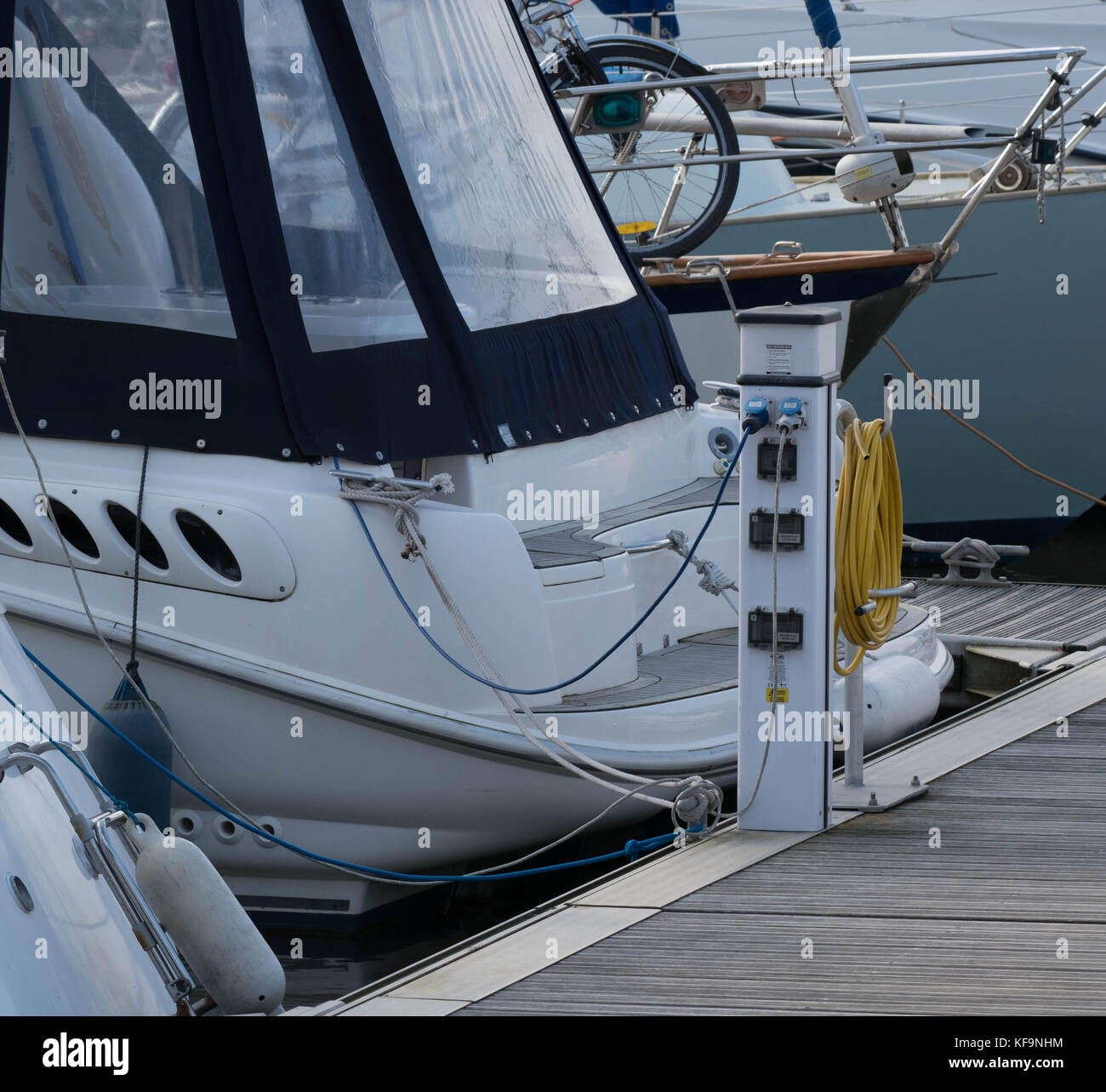 A yacht stern moored on a marina pontoon plugged into the electricity ...