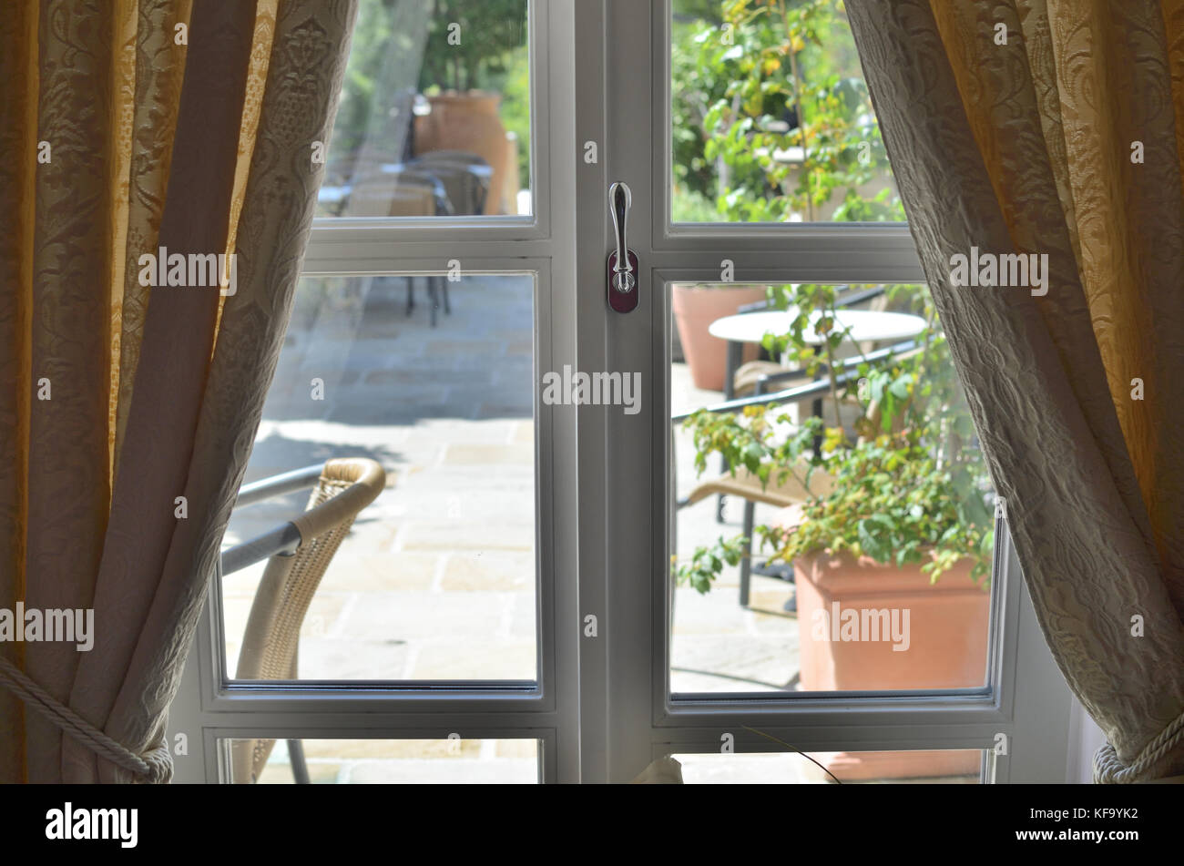 View through white vintage style window to a lush plants on a terrace ...
