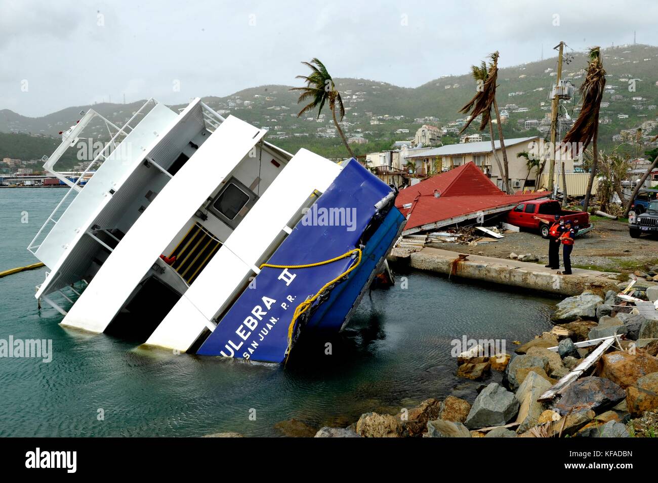 U.S. Coast Guard officers inspect a damaged and partially-sunk boat ...