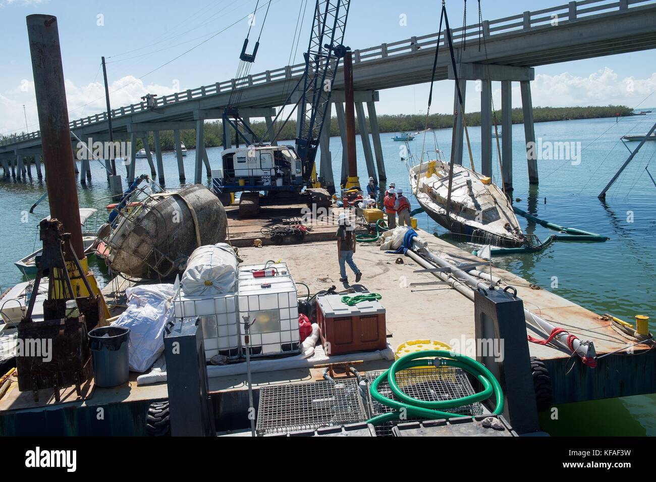 U.S. Coast Guard officers and response crews remove damaged boats from ...