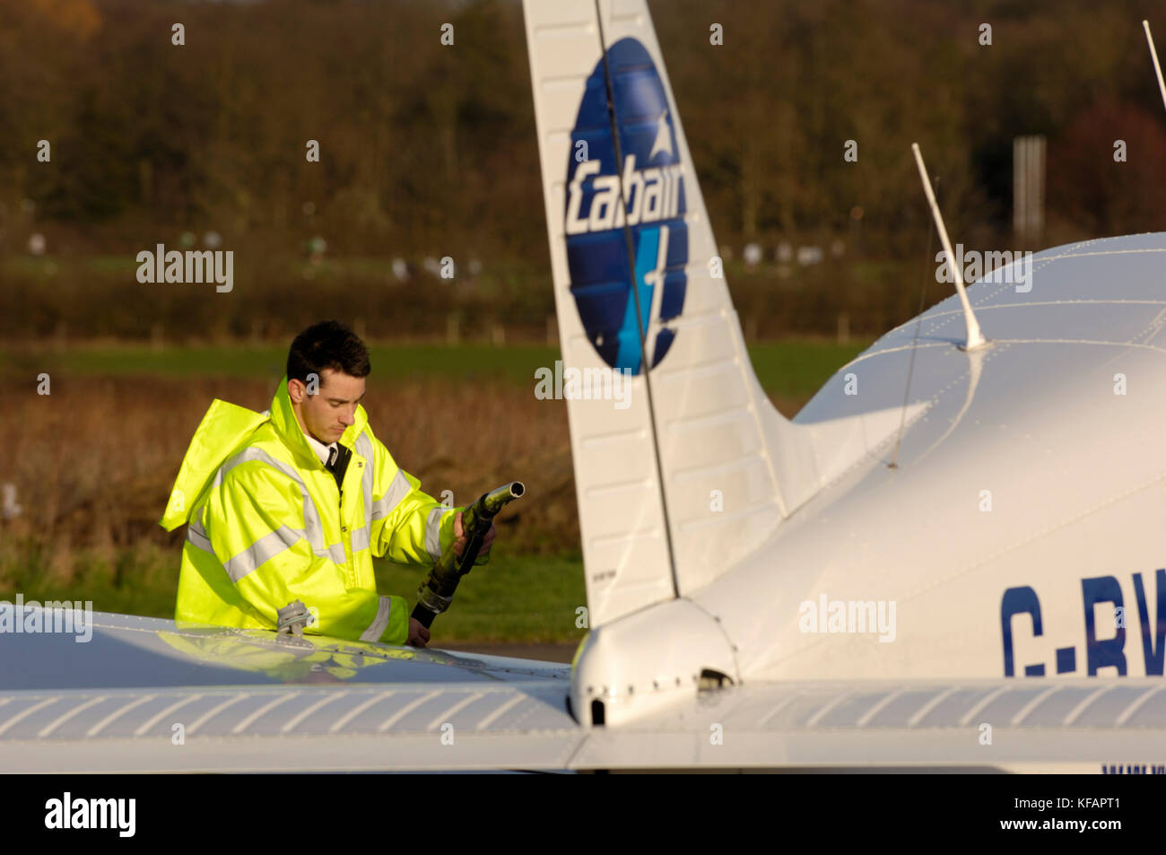 an airport worker wearing a yellow tabard refuelling a Cabair Piper PA ...