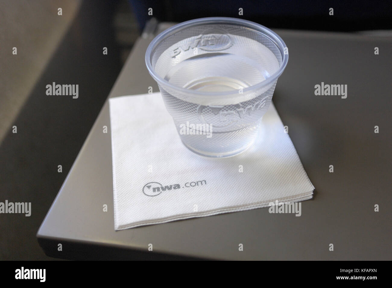 a plastic cup of drinking water and a paper napkin in the economy-class ...