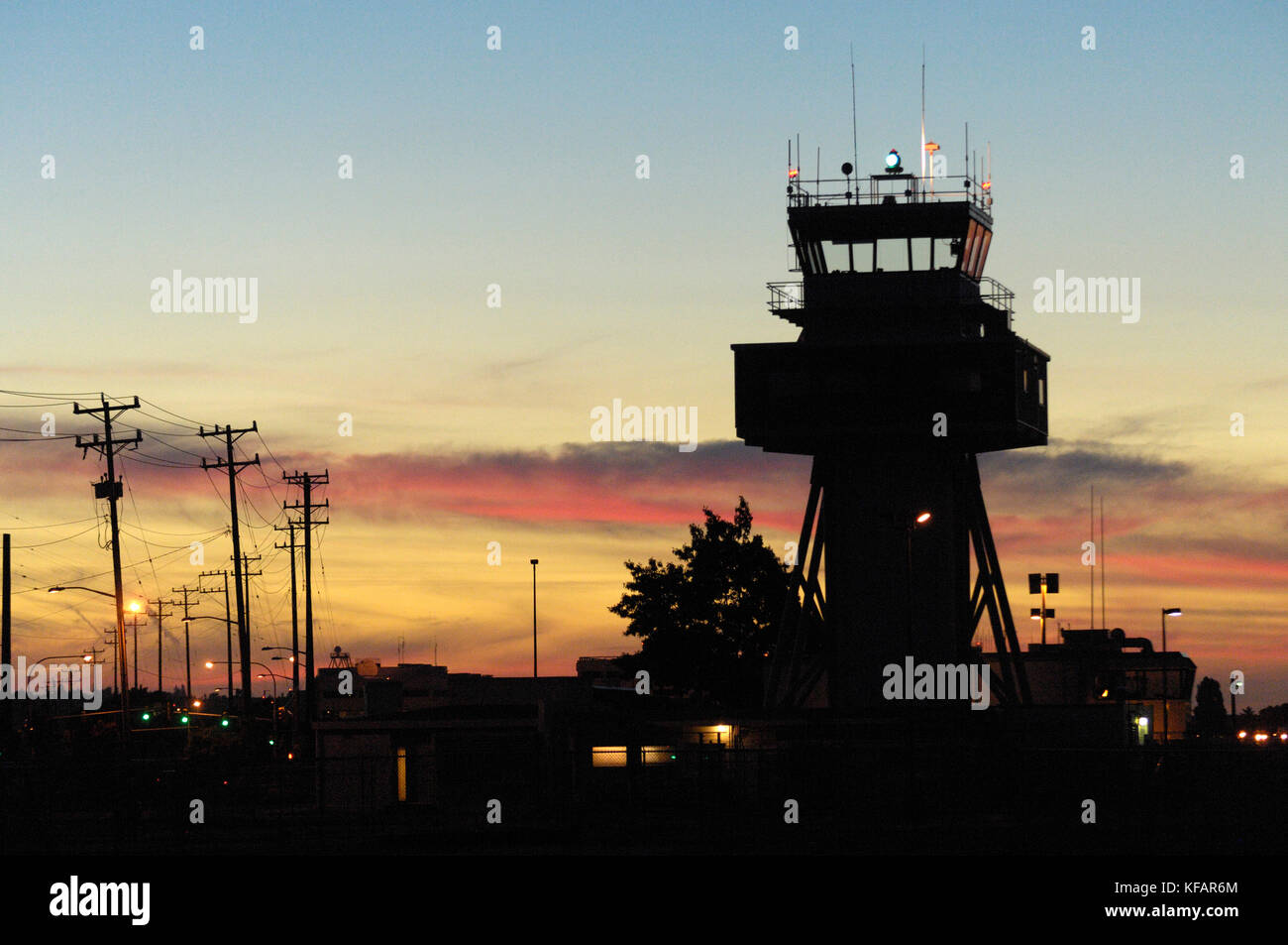 air traffic control-tower at dusk with lights on, green rotating-beacon ...