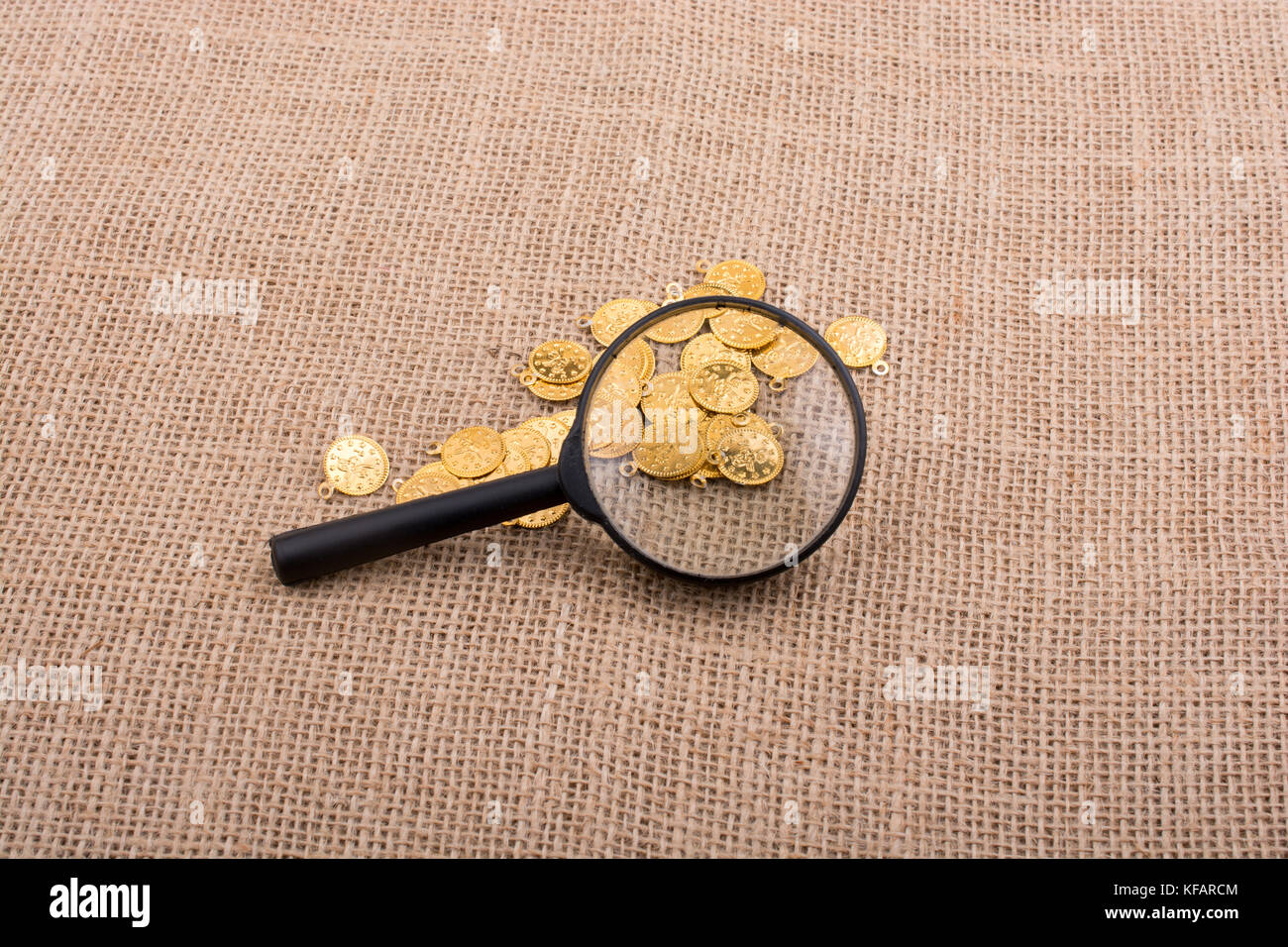 Plenty of fake gold coins behind magnifying glass Stock Photo - Alamy