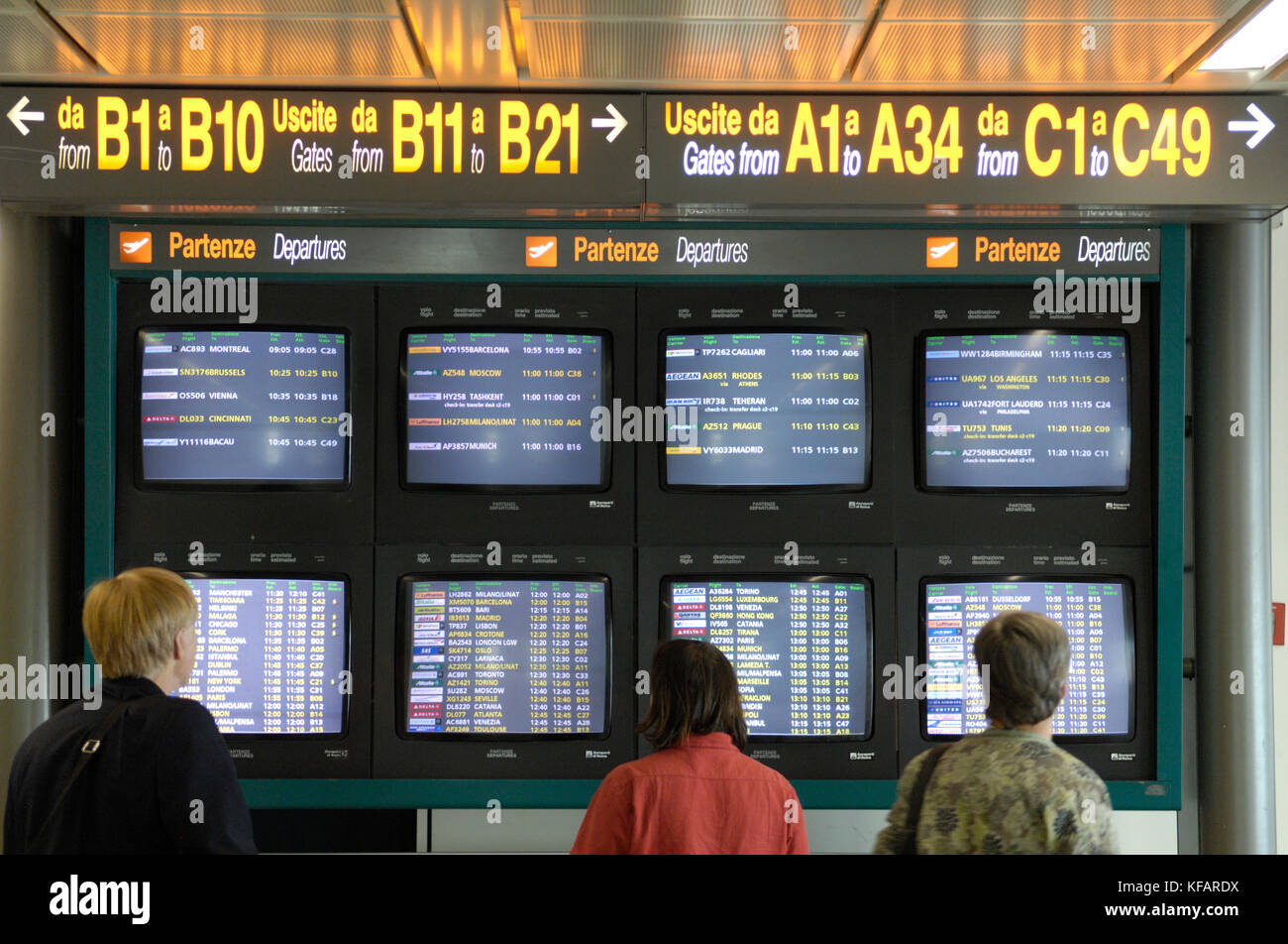passengers looking at the flight-information screens with signs for ...