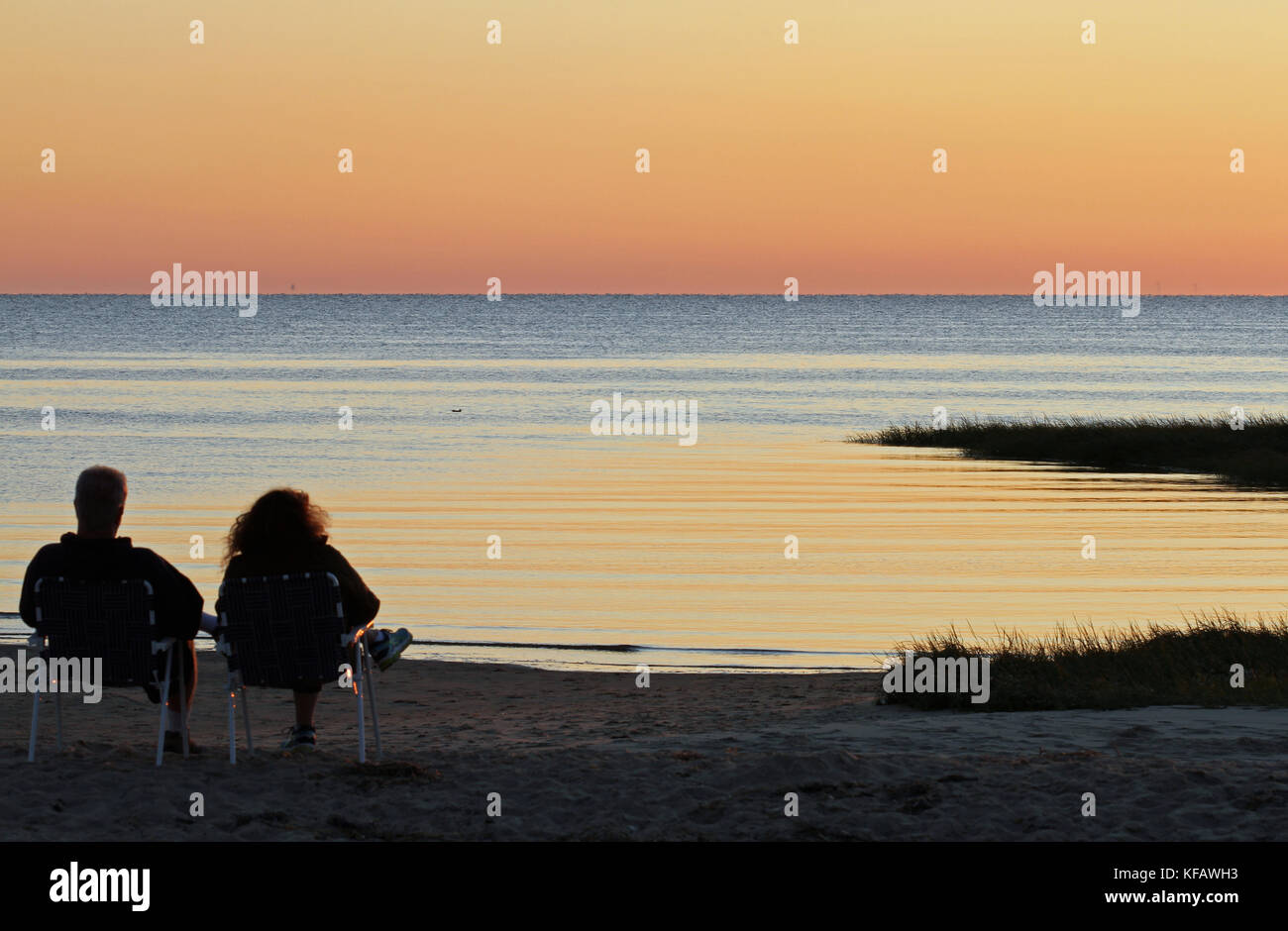 A silhouette of a couple watching a sunset at First Encounter Beach on ...