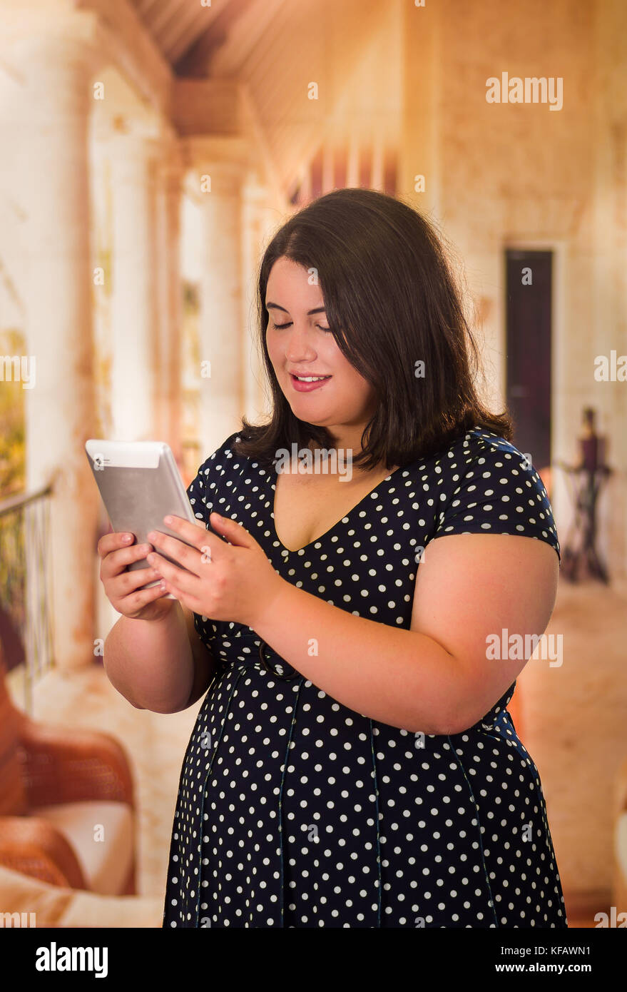 Close up of beautiful fat woman in a beautiful dress using her tablet ...