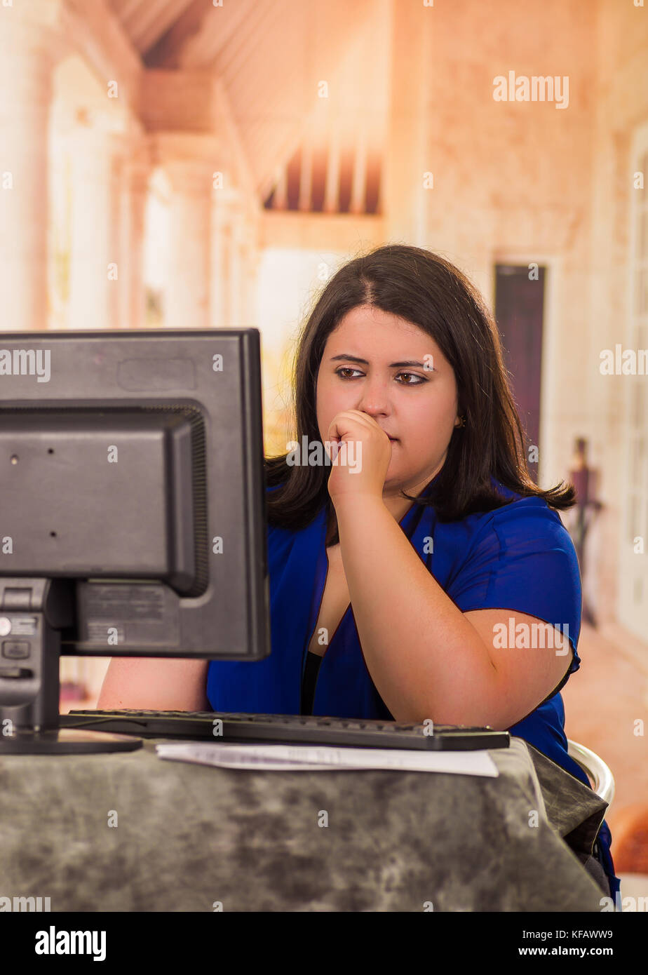 Portrait of worried fat woman working on laptop while sitting in front ...