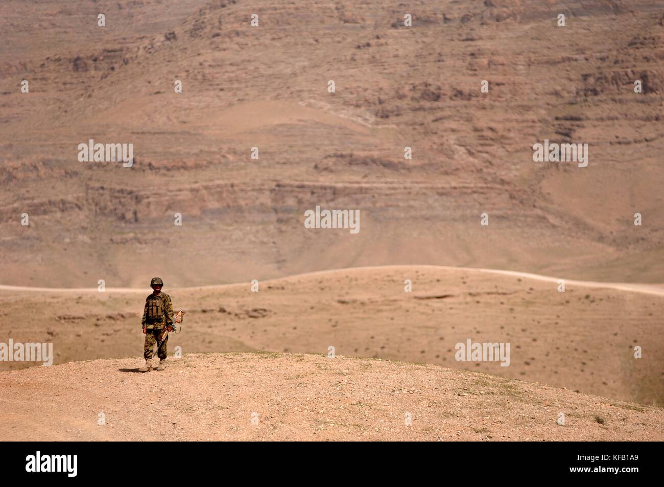 An Afghan National Army soldier stands guard on a hill top during ...