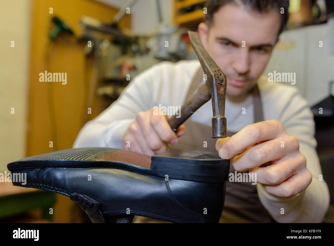 shoemaker hammering on a shoe in workshop Stock Photo - Alamy