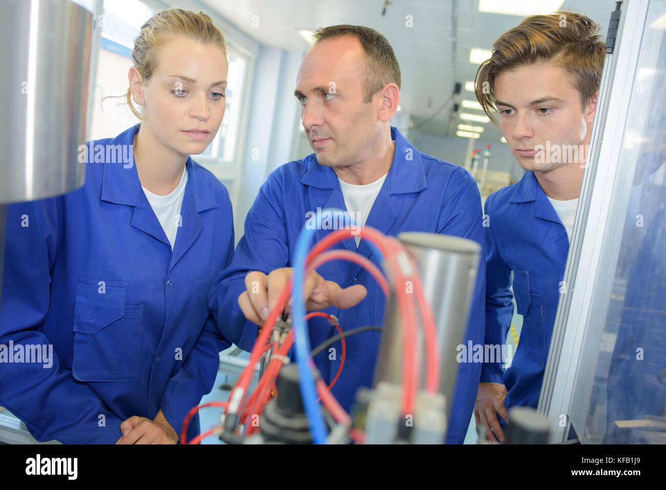Tradesman explaining machinery to apprentices Stock Photo - Alamy