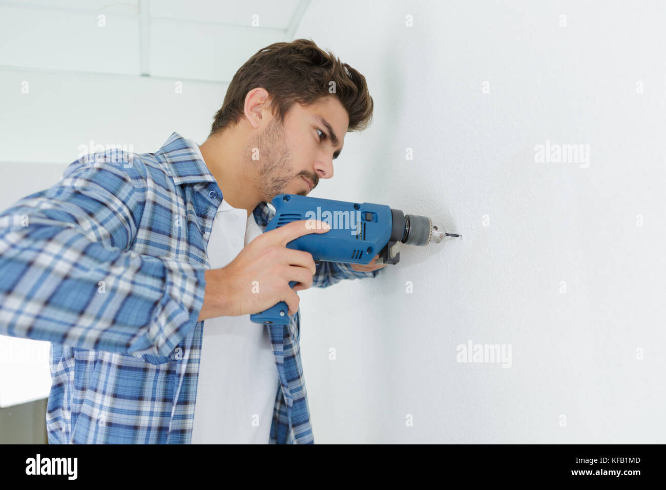 male builder drilling holes in wall at construction site Stock Photo ...