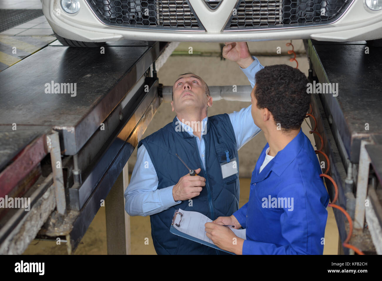 mechanic and trainee working under car Stock Photo - Alamy