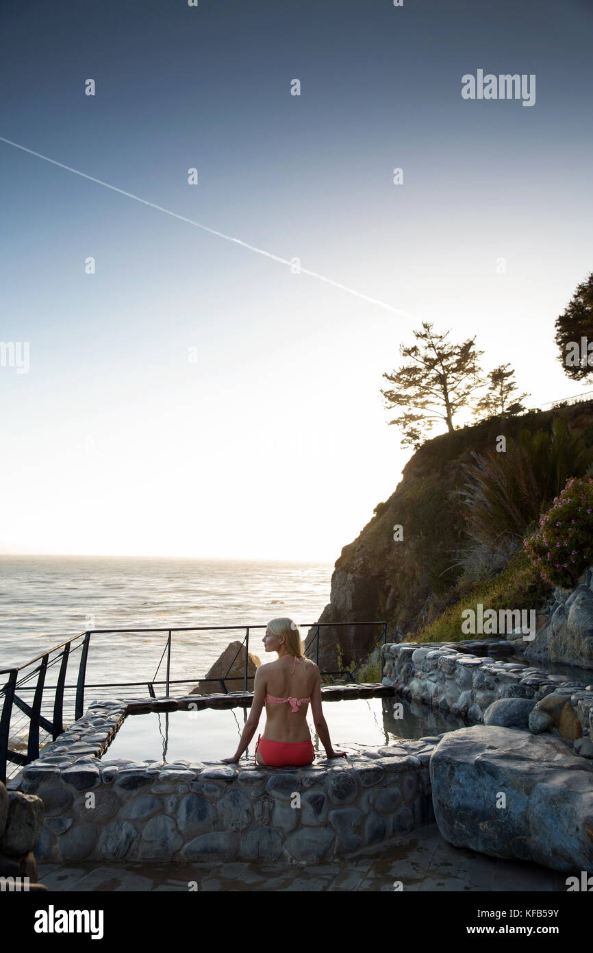 USA, California, Big Sur, Esalen, a woman sits on the edge of the hot ...