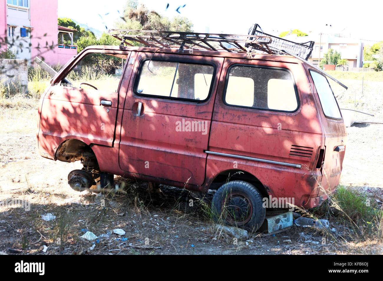 A battered neglected and abandoned people carrier van lies rusting away ...