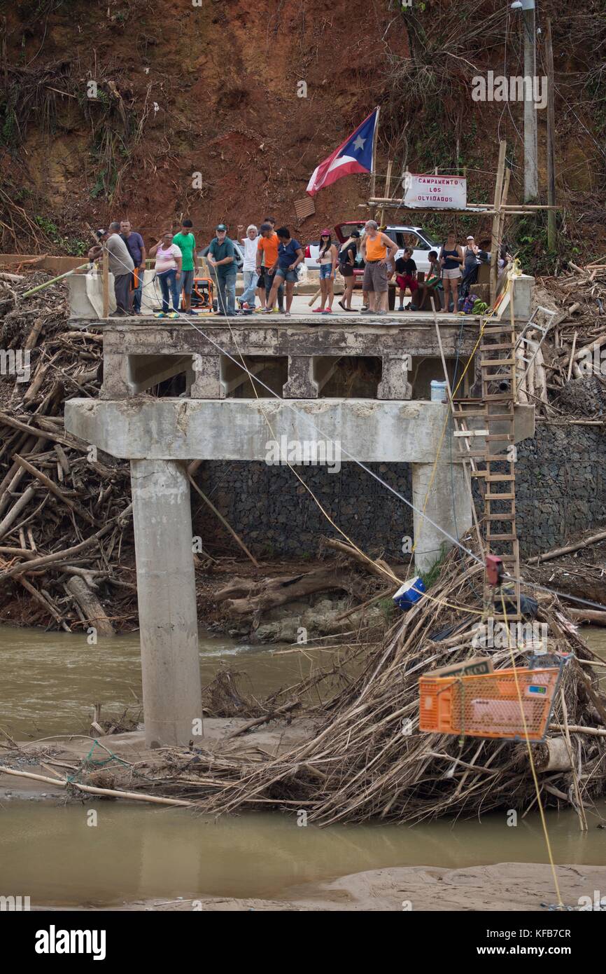 Puerto Rican residents isolated by a broken bridge gather by the Rio ...