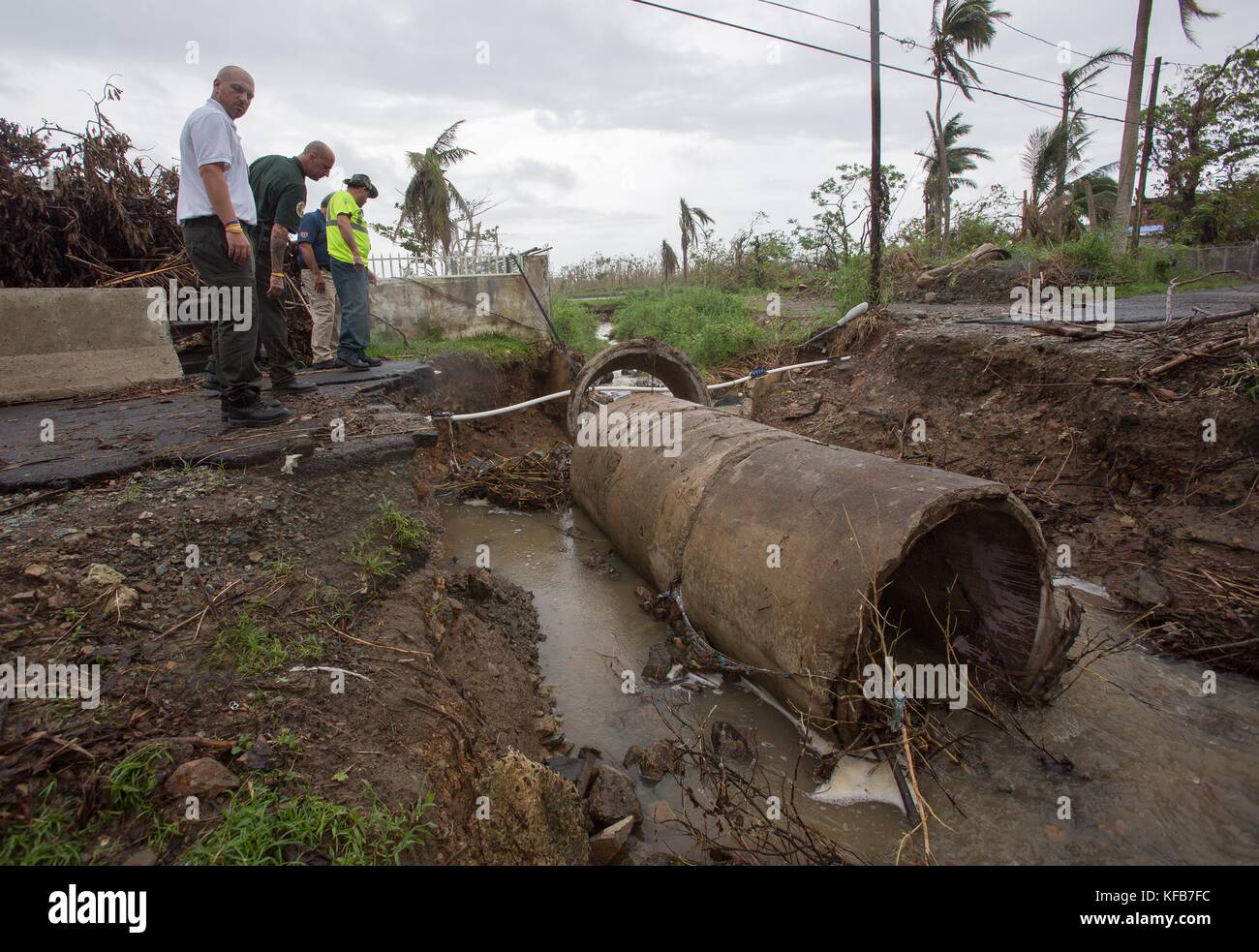 U.S. Department of Sanitation employees inspect a damaged road in the ...