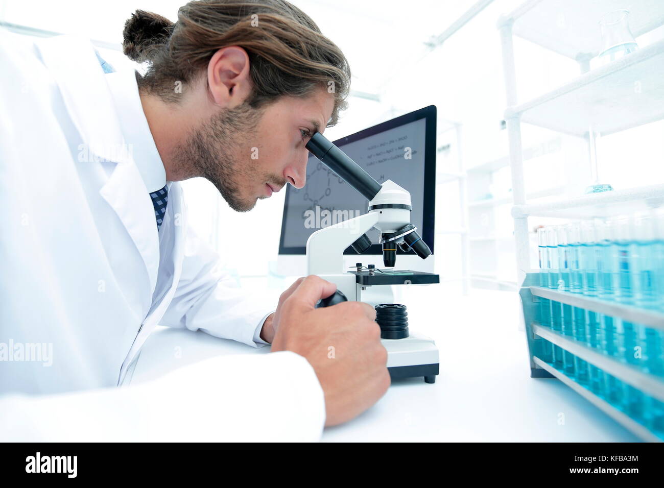 Young laboratory scientist looking at microscope in laboratory Stock ...