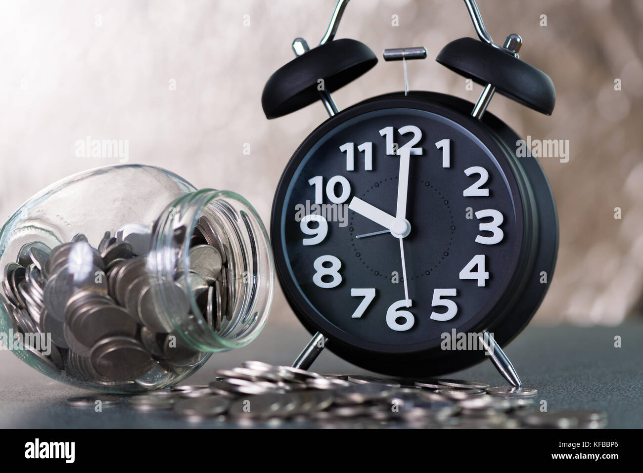 Alarm clock and step of coins stacks with coin in glass jar on working ...