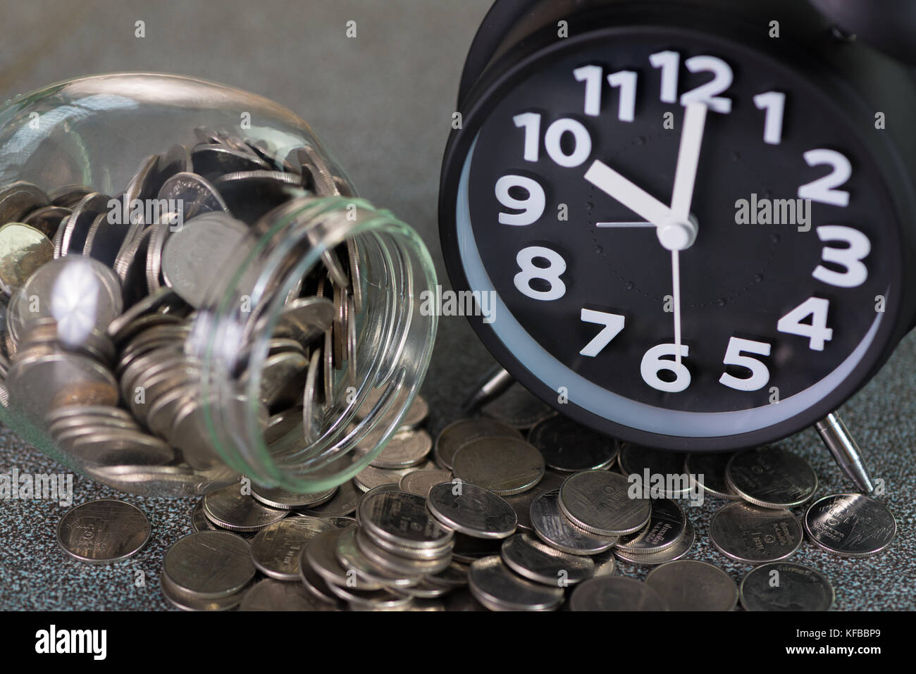Alarm clock and step of coins stacks with coin in glass jar on working ...
