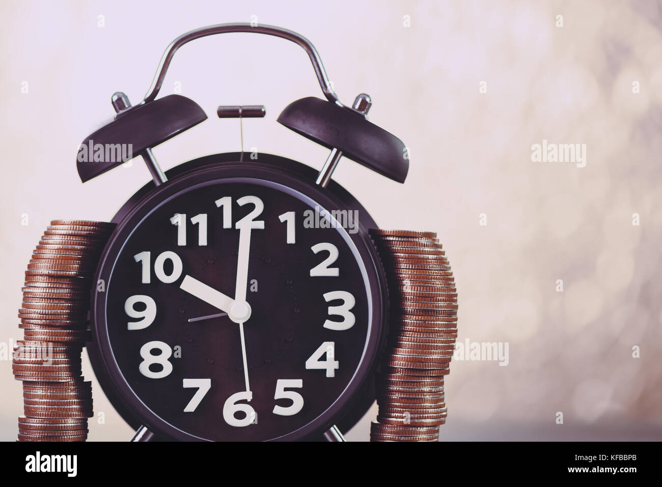 Alarm clock and piles of coin on working table, time for savings money ...