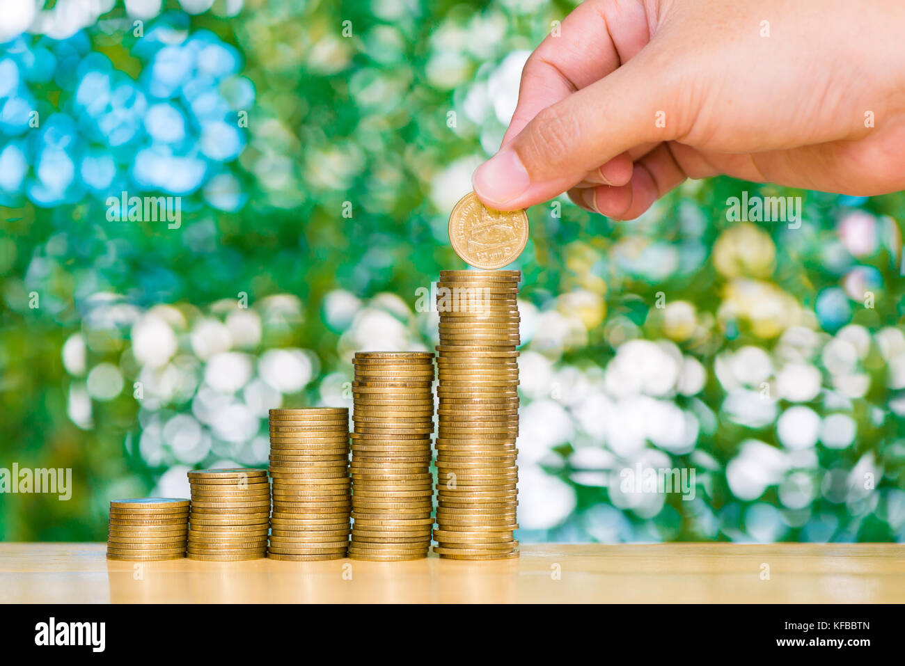 Woman hand put coin on step of coins stacks and gold coin money in the ...