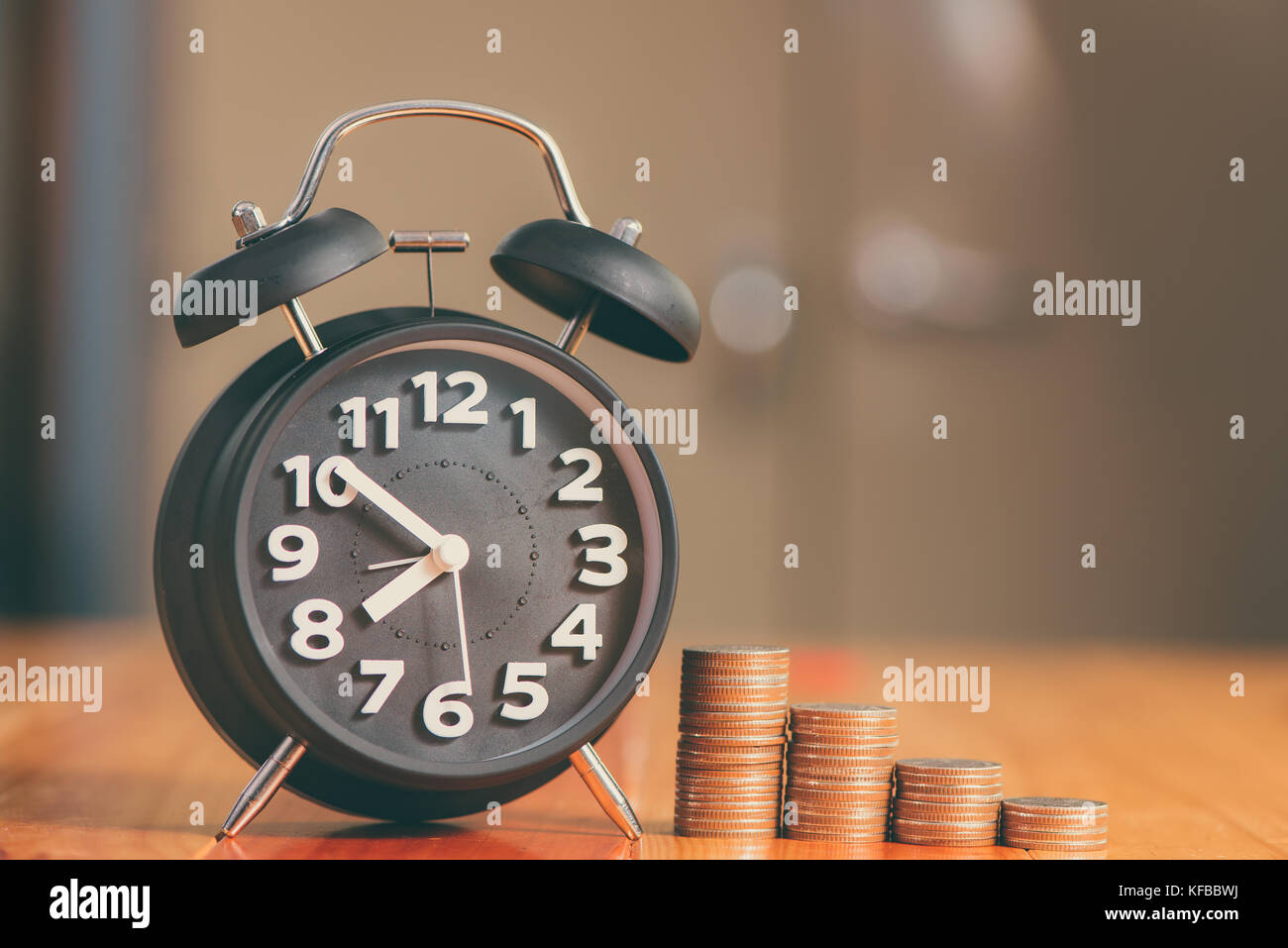 Alarm clock and step of coins stacks on working table, time for savings ...