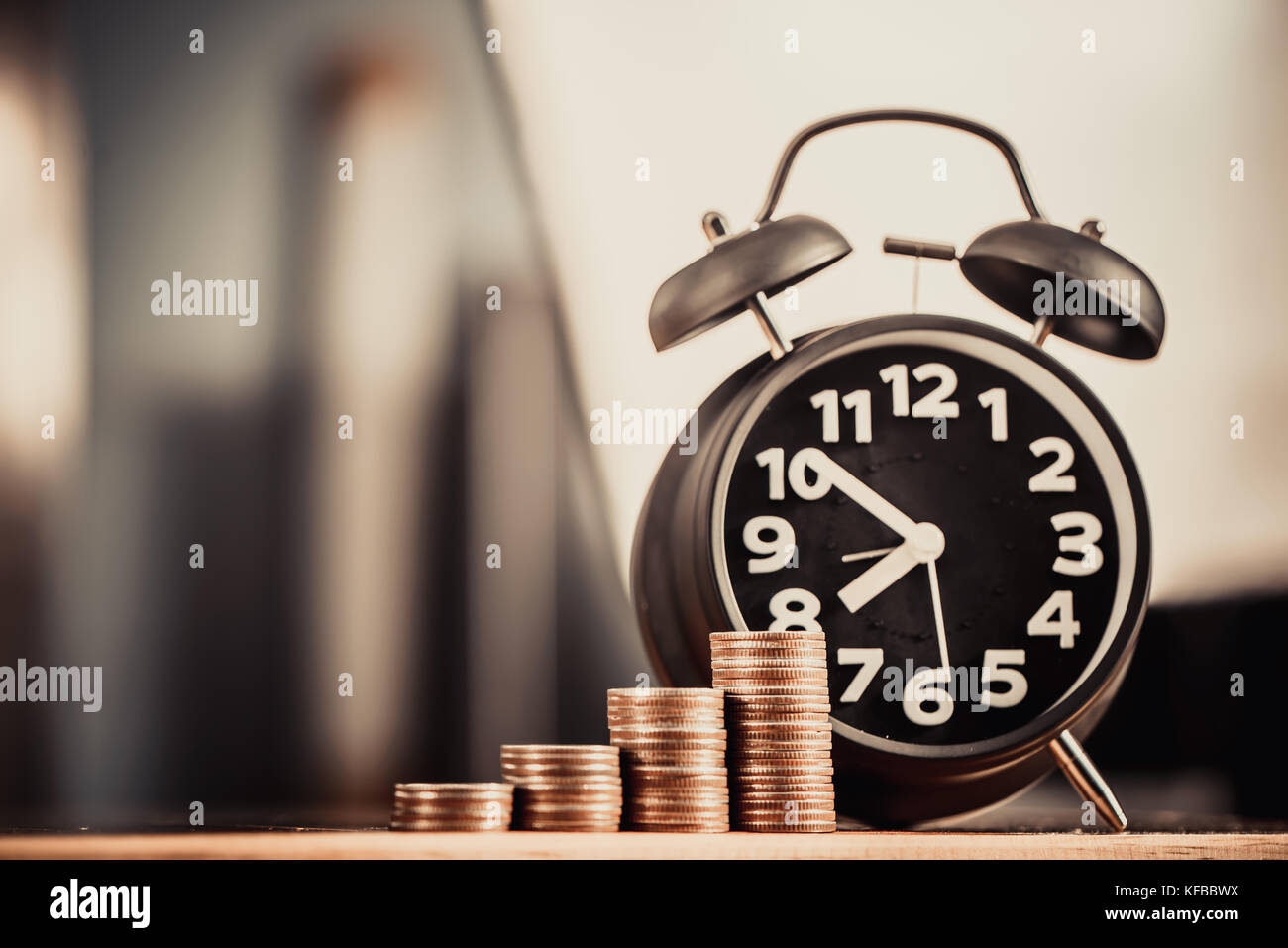Alarm clock and step of coins stacks on working table, time for savings ...