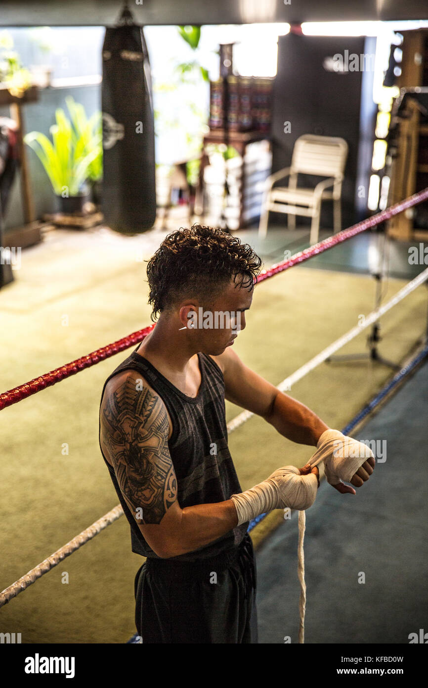 USA, Oahu, Hawaii, an up and coming boxer prepares his hands for a ...
