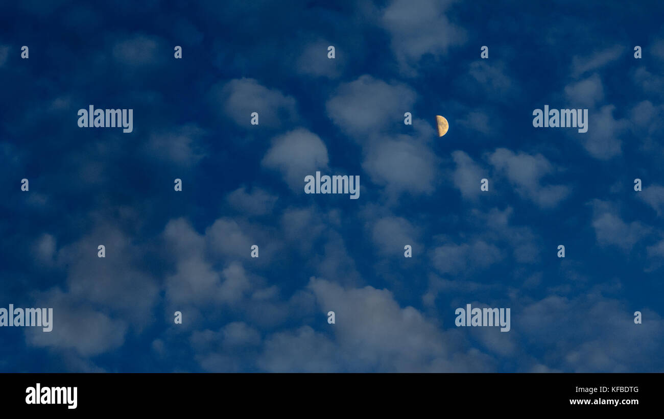 Yellow half moon in the clouds at dusk Stock Photo - Alamy