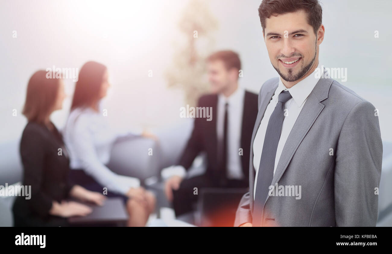 Successful business man standing with his staff in background at office ...