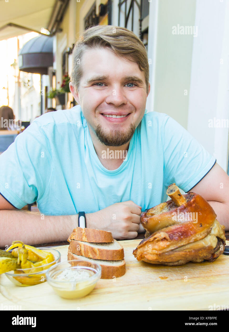 Young man eating smoked pork leg meat and drinking beer Stock Photo - Alamy