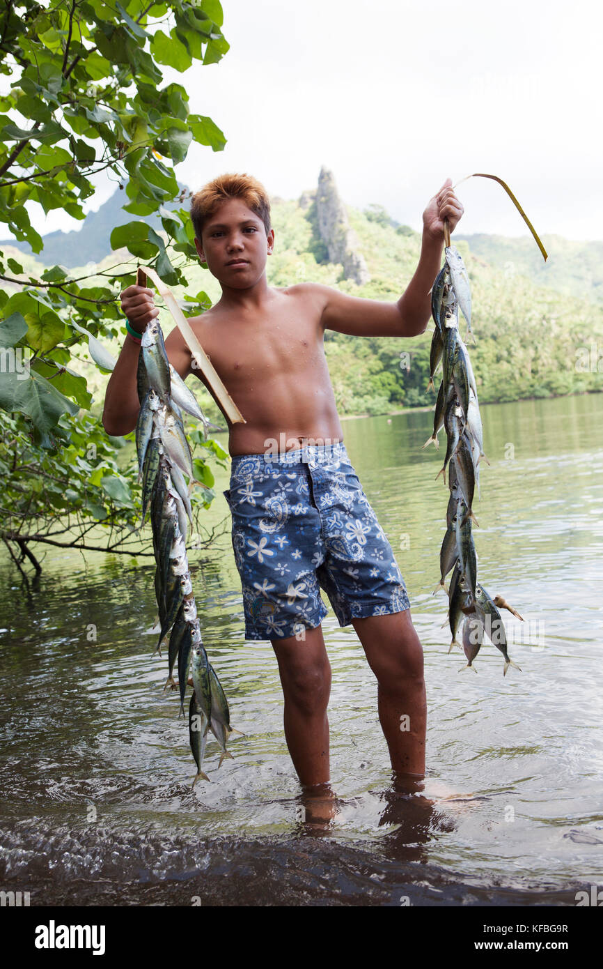 FRENCH POLYNESIA, Moorea. A young boy with his catch which he will ...