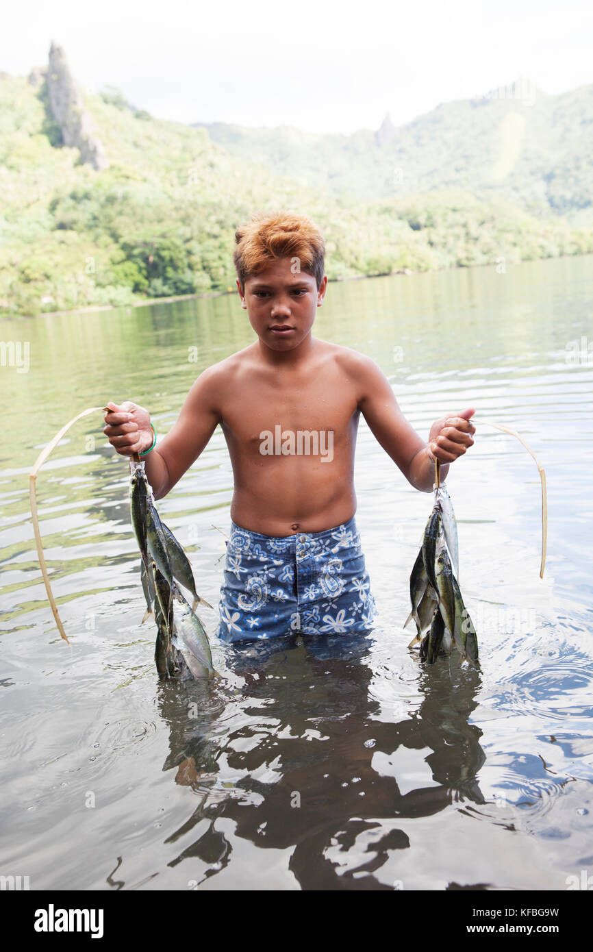 FRENCH POLYNESIA, Moorea. A young boy with his catch which he will ...