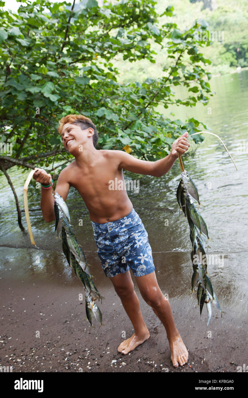 FRENCH POLYNESIA, Moorea. A young boy with his catch which he will ...