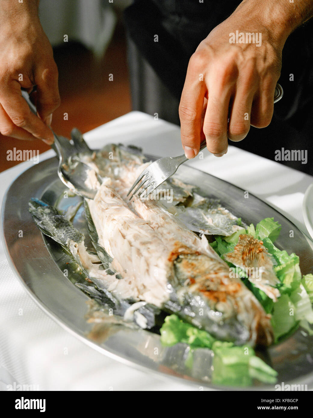 ITALY, Venice, close-up of waiter's hands serving fish in Mistra ...