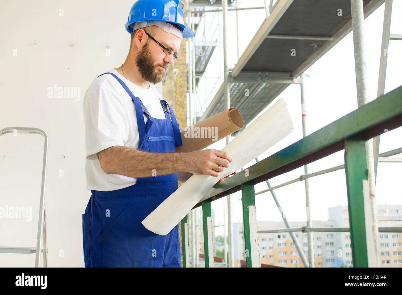 Construction worker in working outfit and in helmet stands at high ...