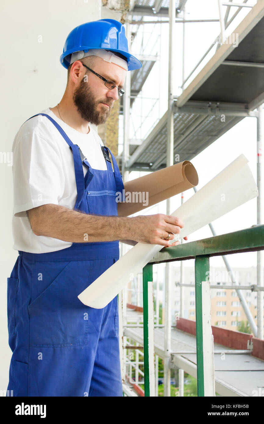 Construction worker in working outfit and in helmet stands at high ...